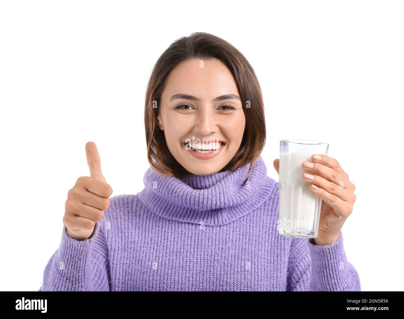 Young woman with glass of fresh milk showing thumb-up on white ...