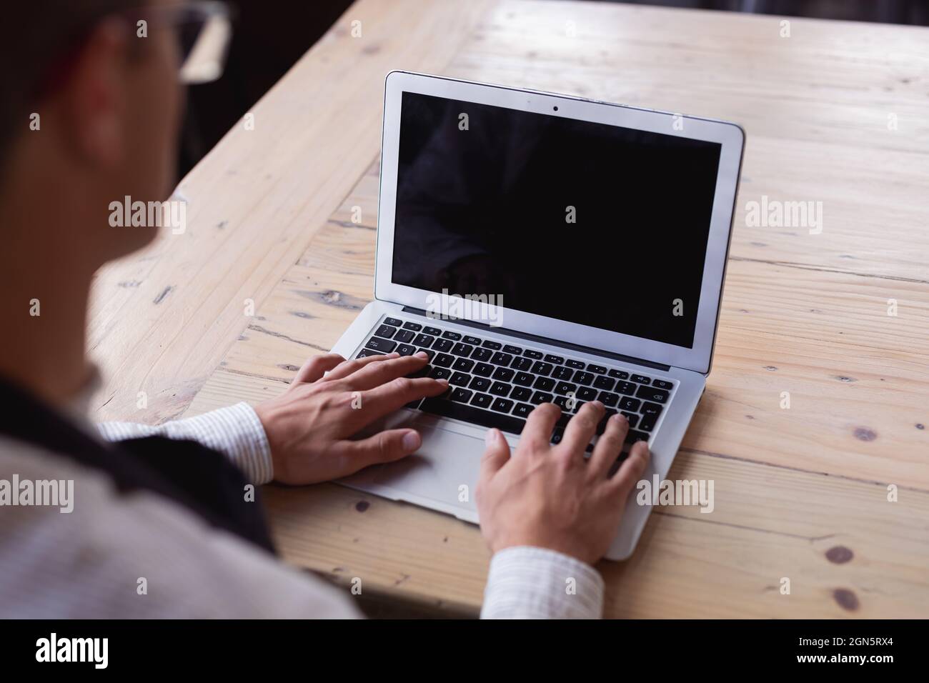 Rear view of caucasian man using laptop at gin distillery Stock Photo ...