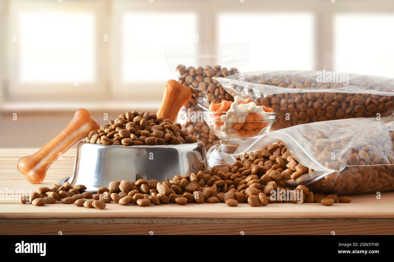 Dog croquettes in sacks and feeder on wooden table with pressed skin ...