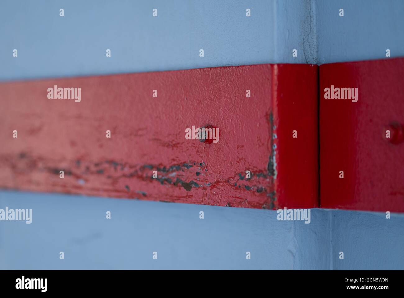 Close-up of bolt emerging from the building wall painted red and blue ...