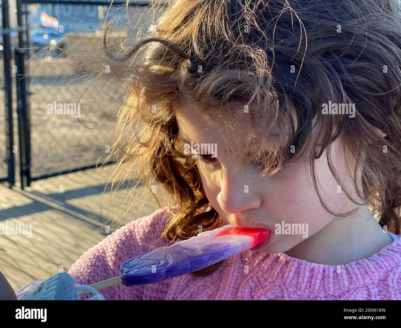 Bright sunny summer day with a young girl close up eating a ice cold ...