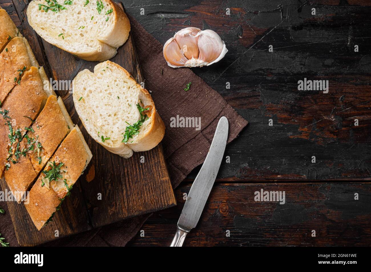 Garlic bread filled compound herb butter set, on old dark wooden table ...