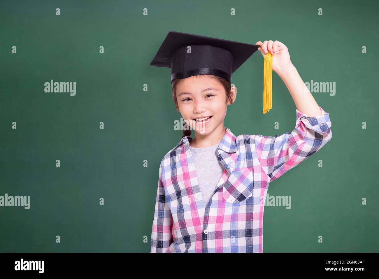 Happy student girl wearing graduation cap.Isolated on green chalkboard ...