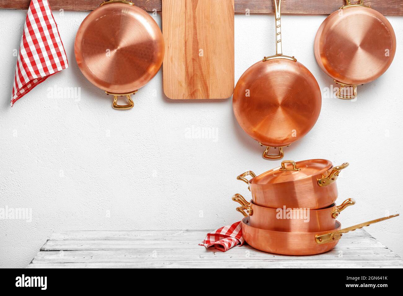 Row of shiny clean copper pans, different size, hung on wooden plank ...