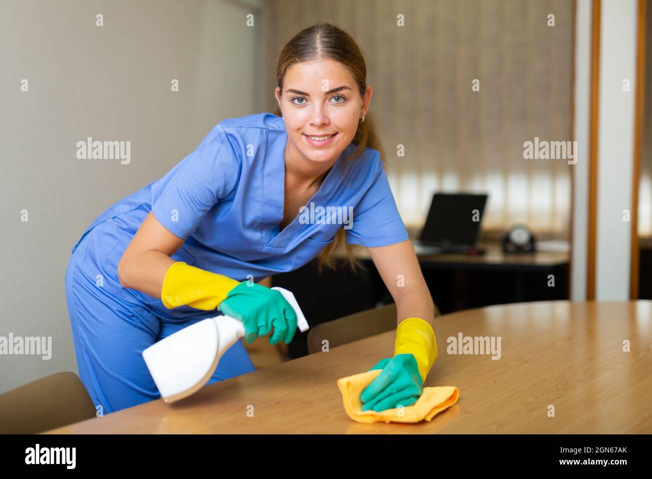 Portrait of a young female worker cleaning an office desk Stock Photo ...