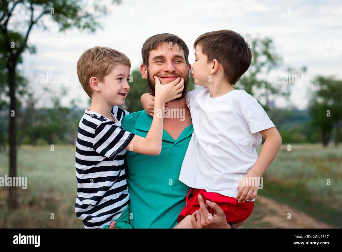 Caring father with two little sons on countryside background. Authentic ...