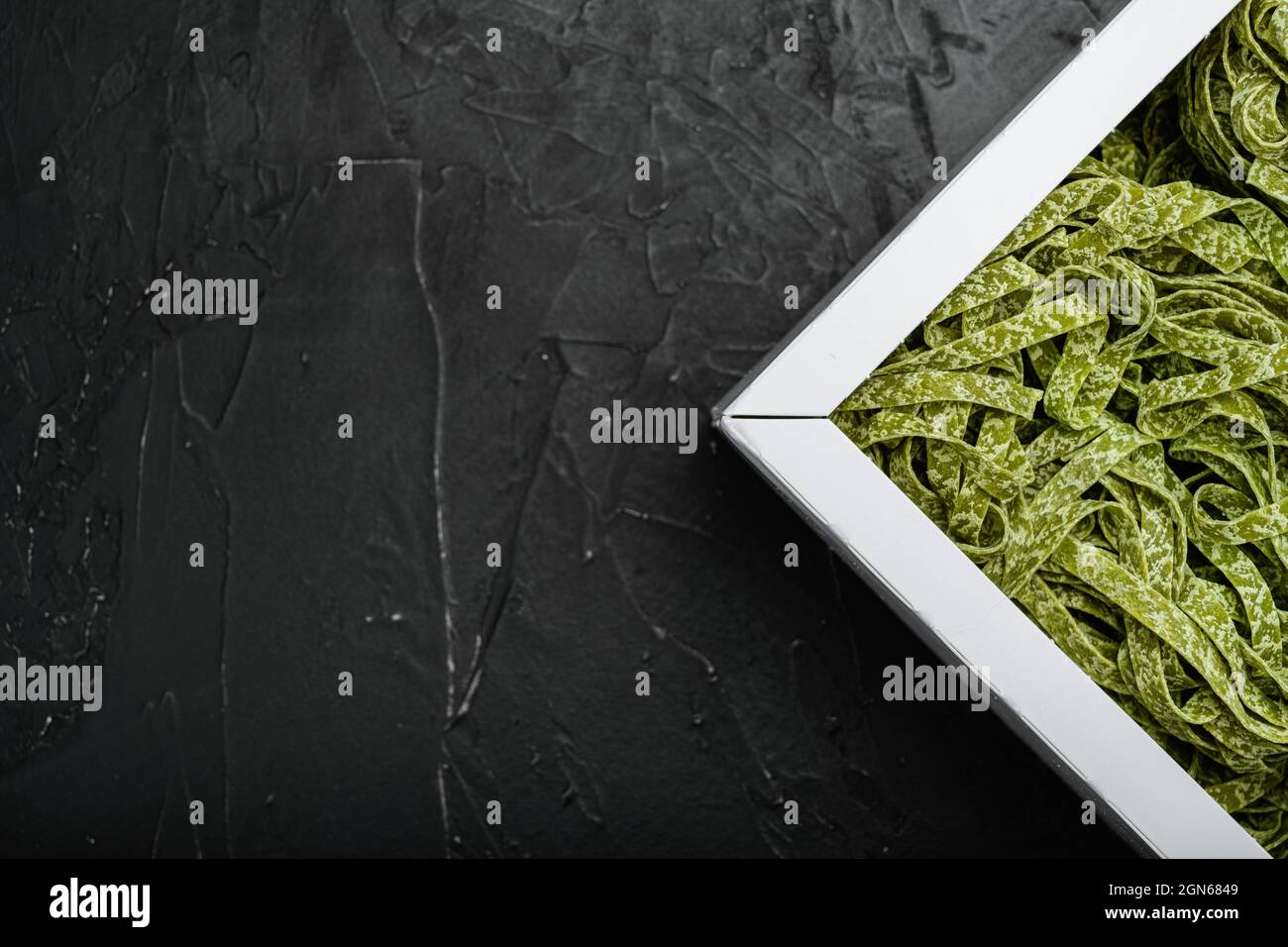 Spinach pasta pack set, on black dark stone table background, top view ...