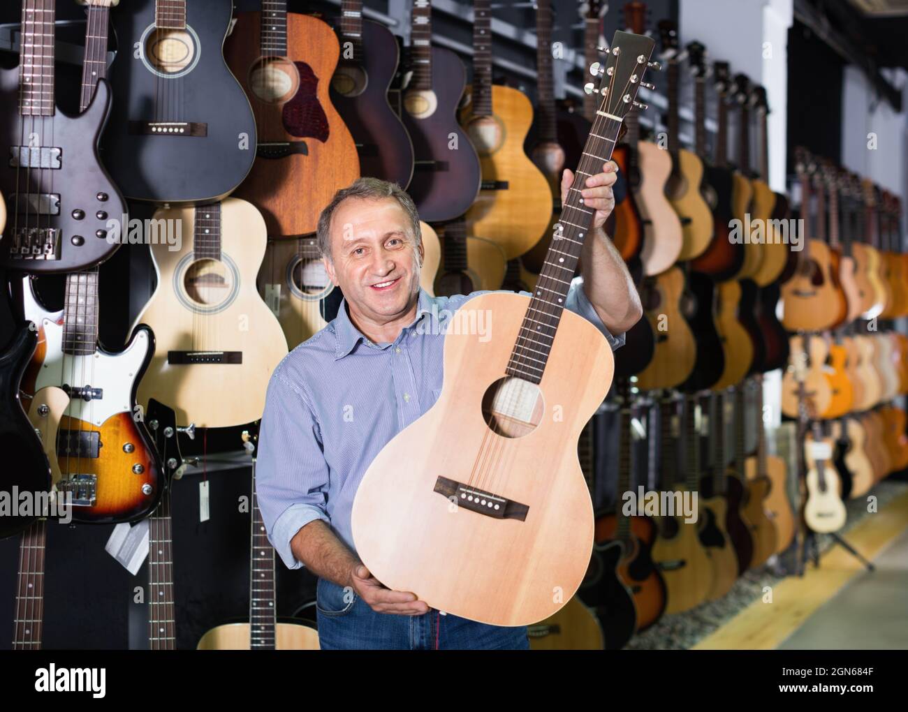 Adult guitarist is standing with acoustic guitar in music store Stock ...