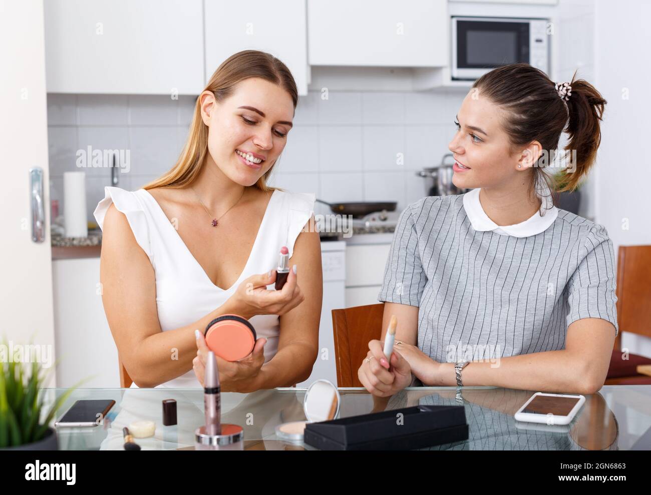 Two young friends applying lipstick hi-res stock photography and images ...