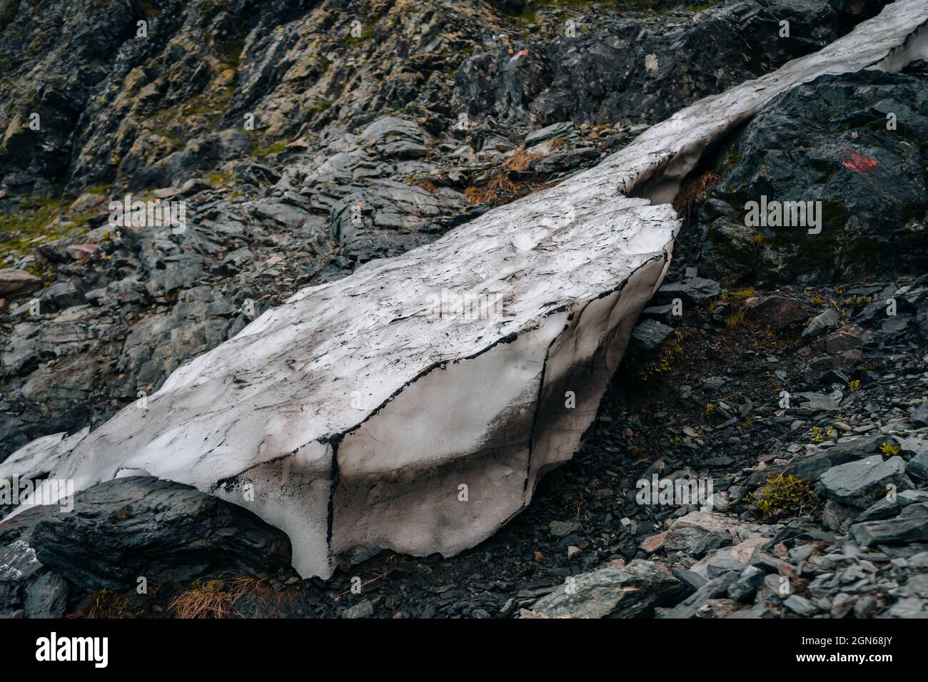 Closeup of the big piece of melting dirty ice on the rocky mountains ...