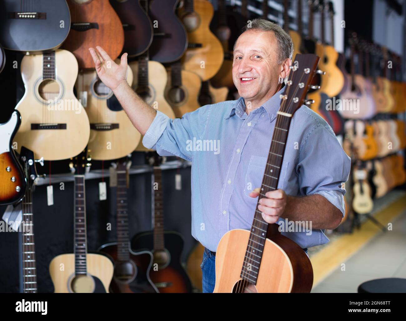 Adult guitarist is standing with acoustic guitar in music store Stock ...