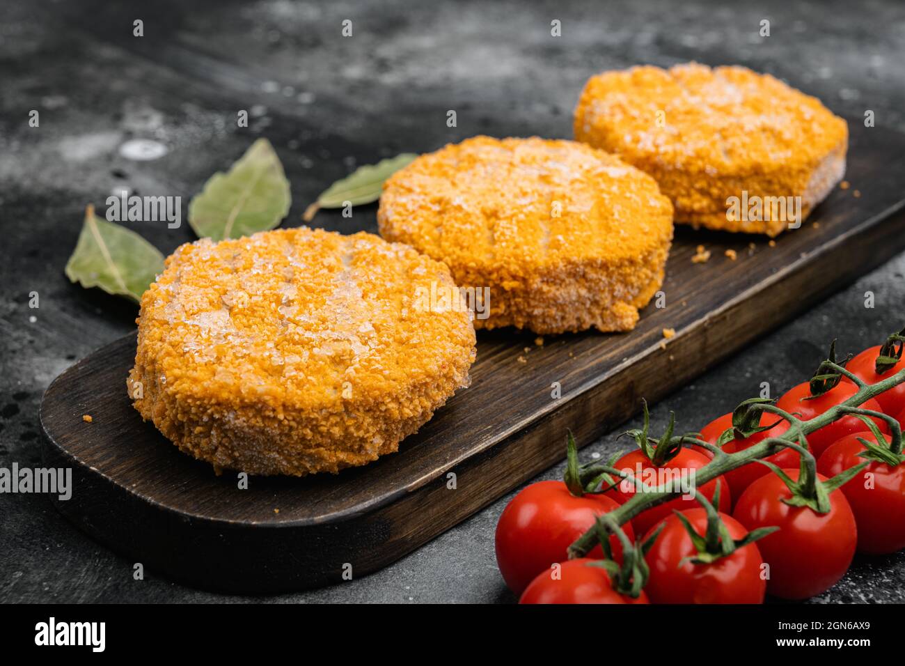 Frozen Breaded fish patties set, on black dark stone table background ...