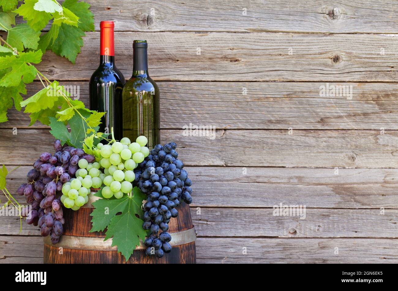 Various colorful grapes and wine bottles on wine barrel on outdoor ...