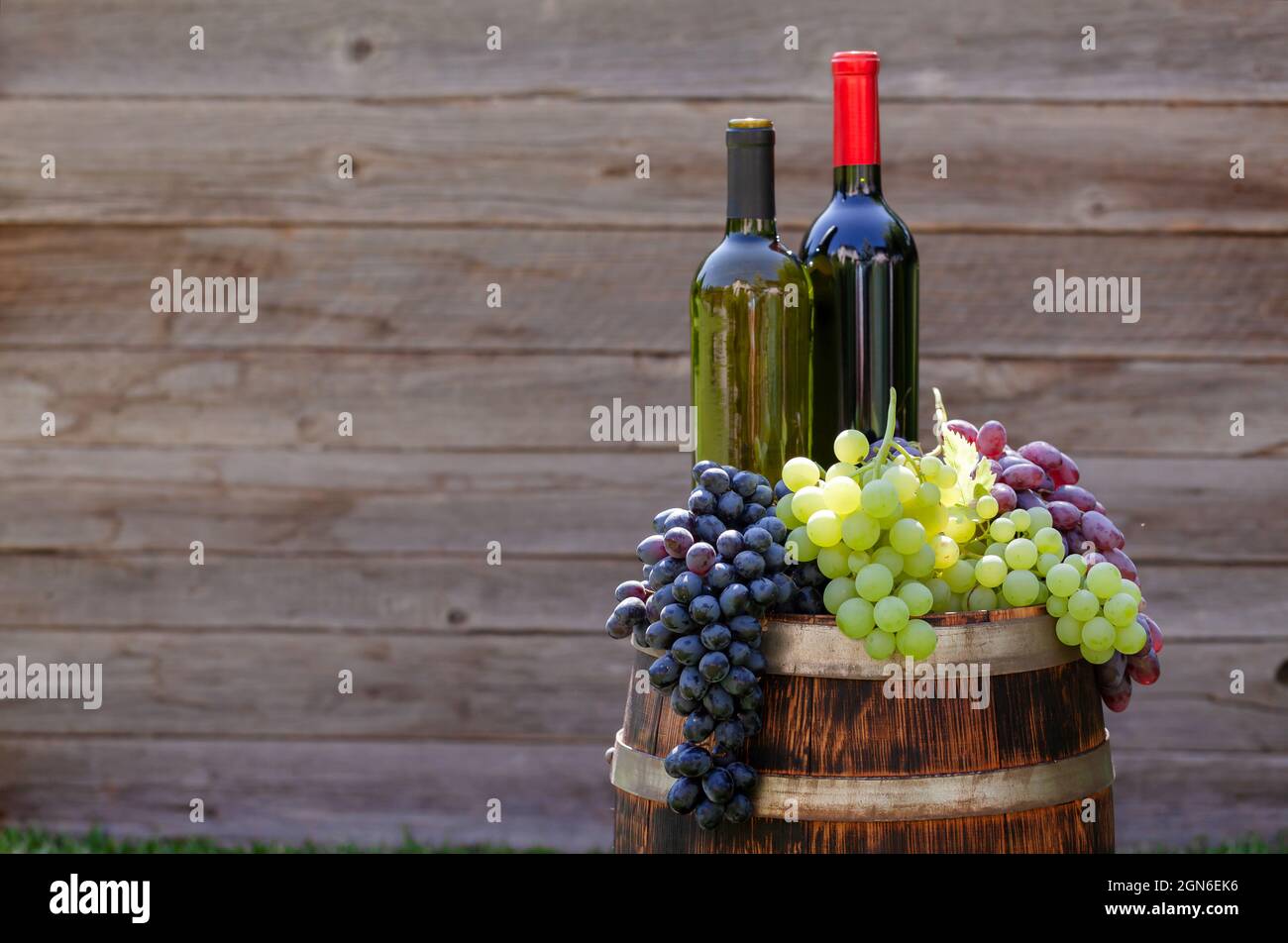 Various colorful grapes and wine bottles on wine barrel on outdoor ...