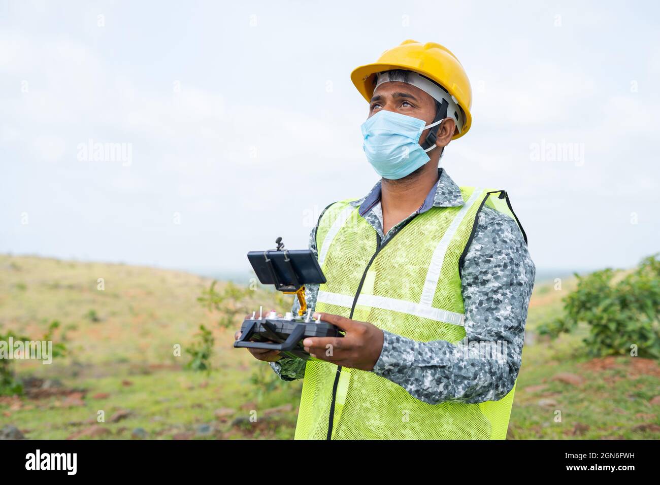 Drone operator with safety helmet and face mask operating drone using ...