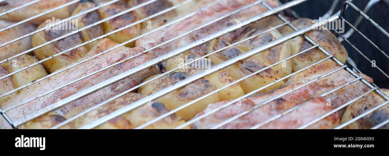 Roast pork and potatoes on wire rack over fire closeup Stock Photo - Alamy