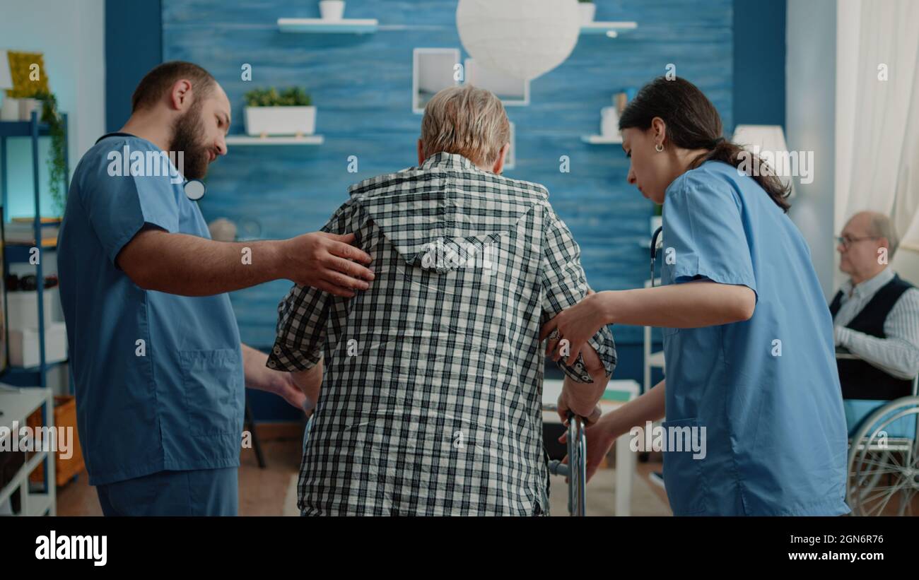 Medical team helping senior woman with disability in nursing home ...