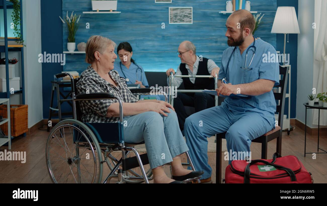 Man nurse consulting elder woman with disability in nursing home ...