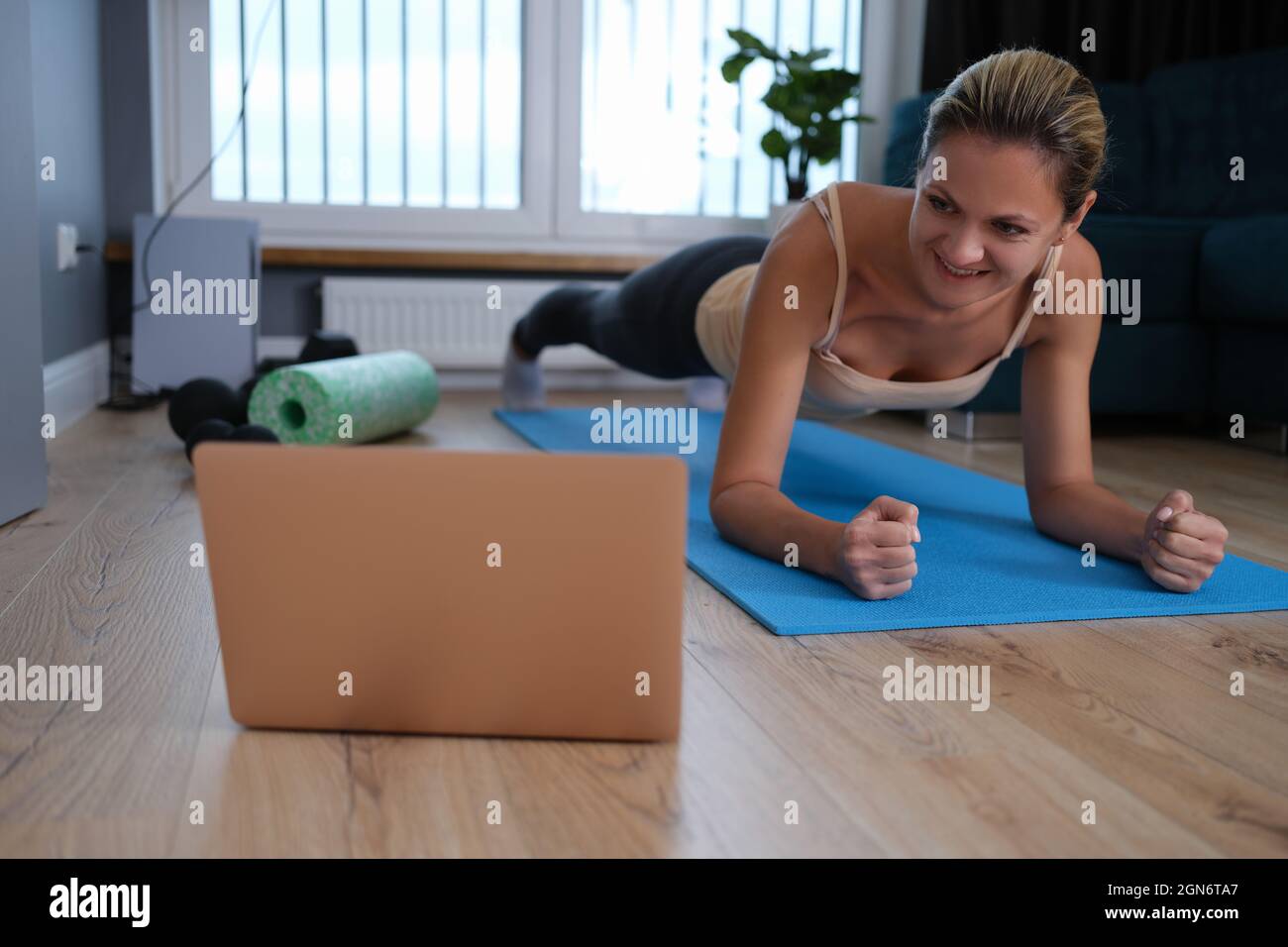Healthy young woman doing plank exercises at home while watching an ...