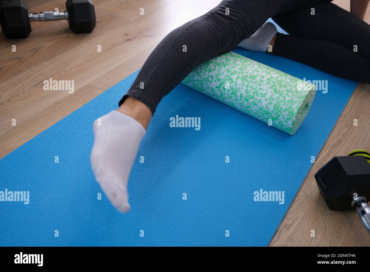 Fitness woman in sportswear lying on yoga mat exercising with foam ...