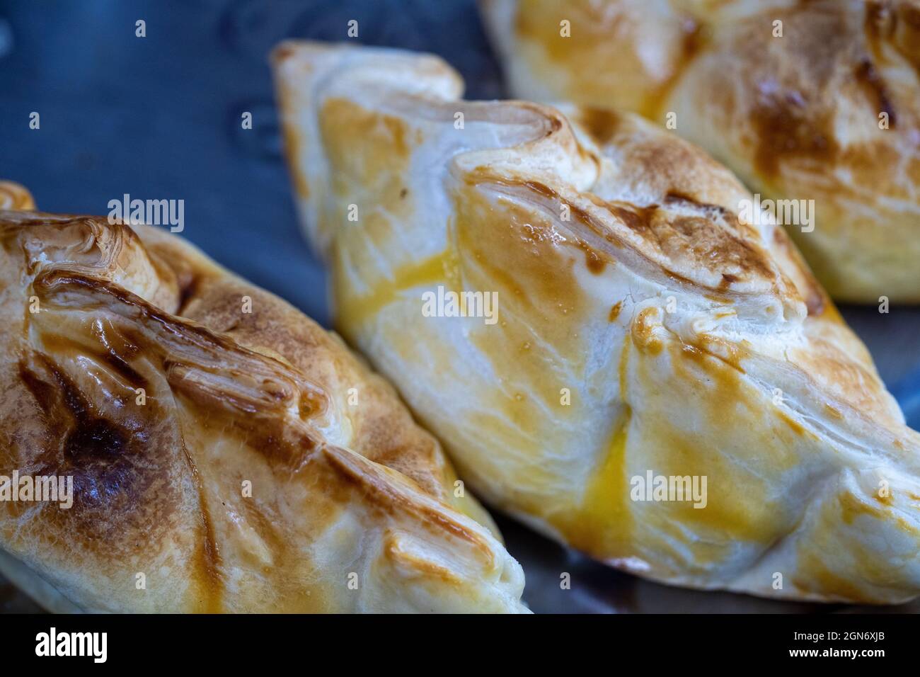 Closeup shot of baked empanadas with ham and cheese on a blue surface ...