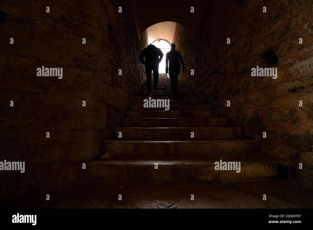 Two people walking to the light in the dark stairs. Afterlife, hope ...