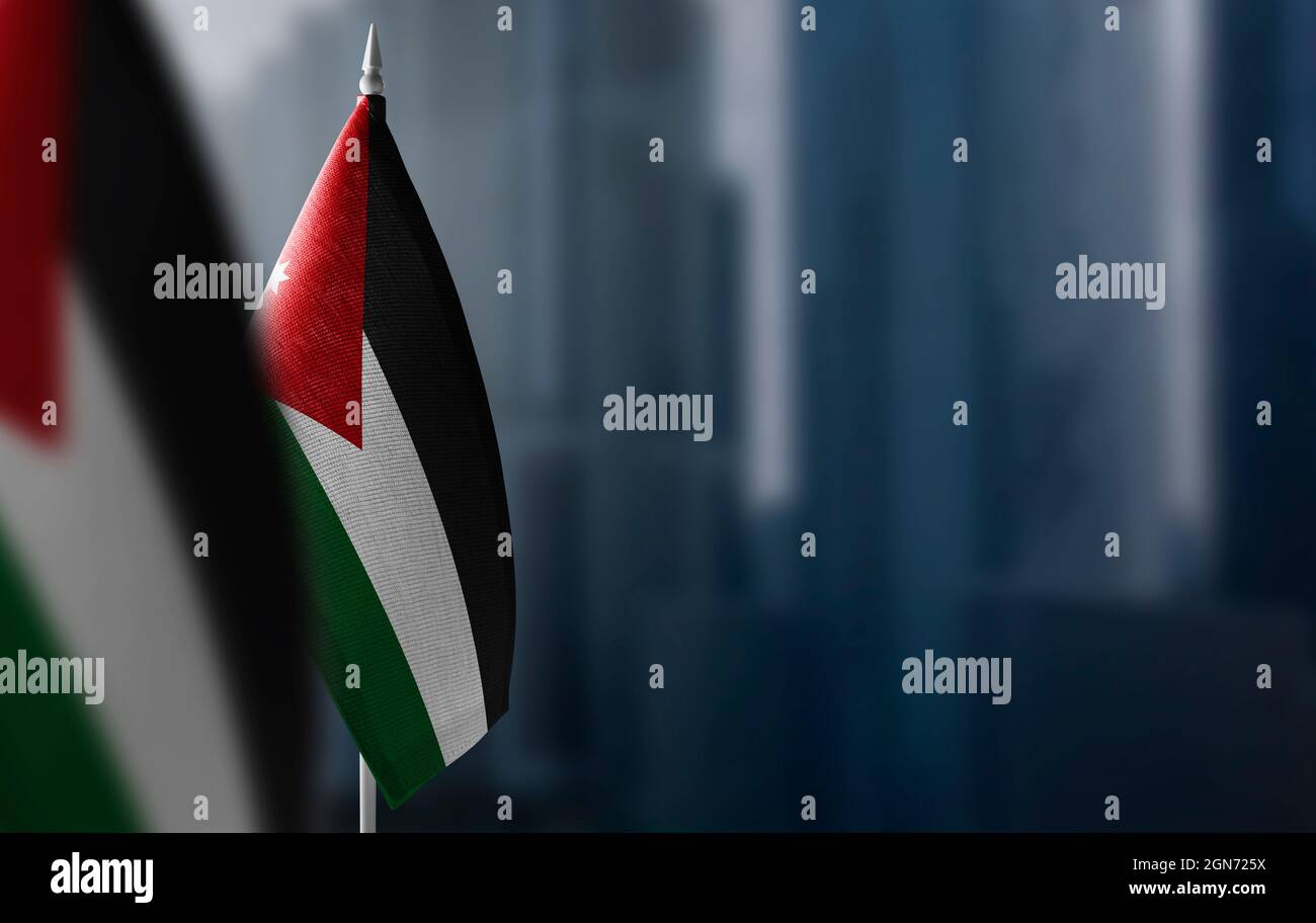 Small flags of Jordan on a blurry background of the city Stock Photo ...