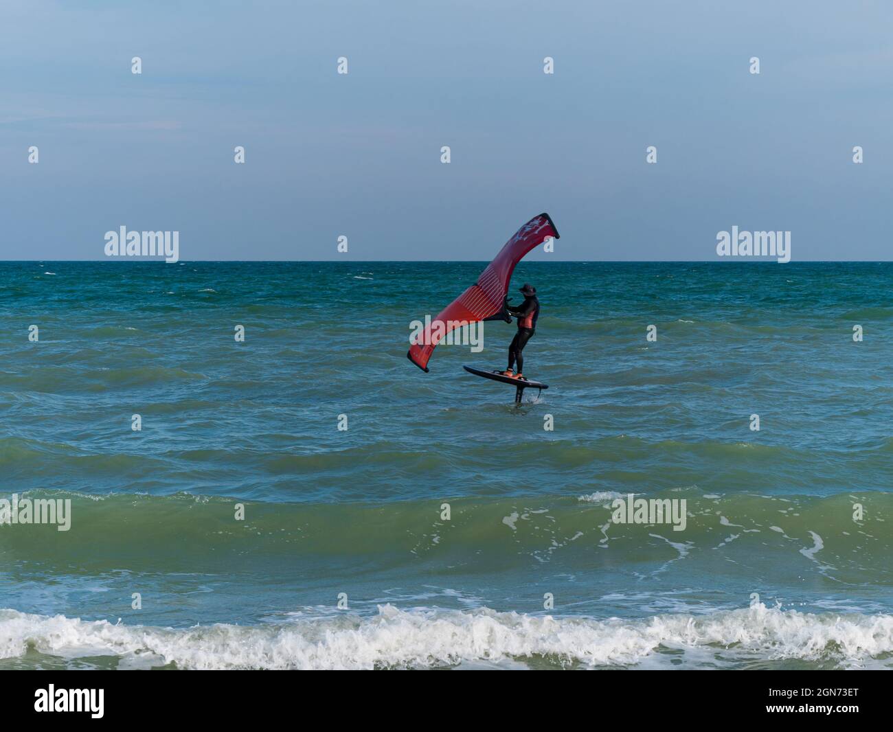 The athlete riding a hydrofoil surfboard using a hand held foil wing on ...