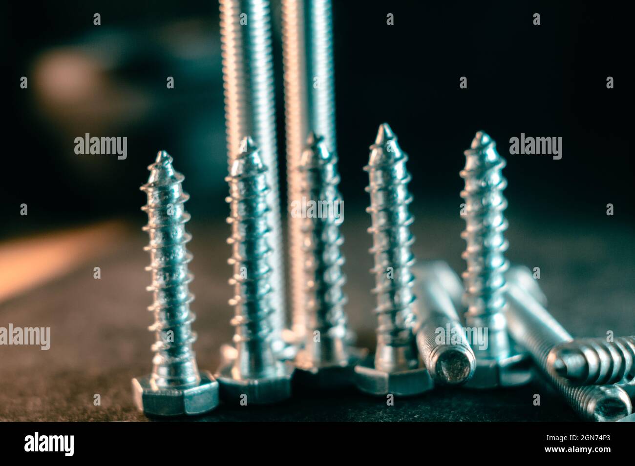 Pile of screws on a blurred background Stock Photo - Alamy