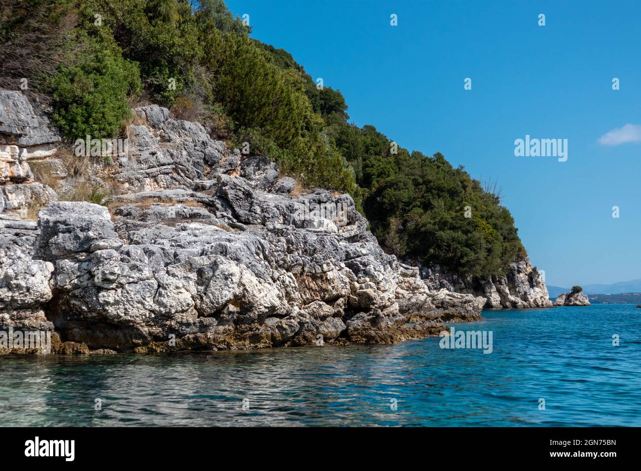 Blue clear Ionian Sea water with scenic green rocky cliffs coast and ...