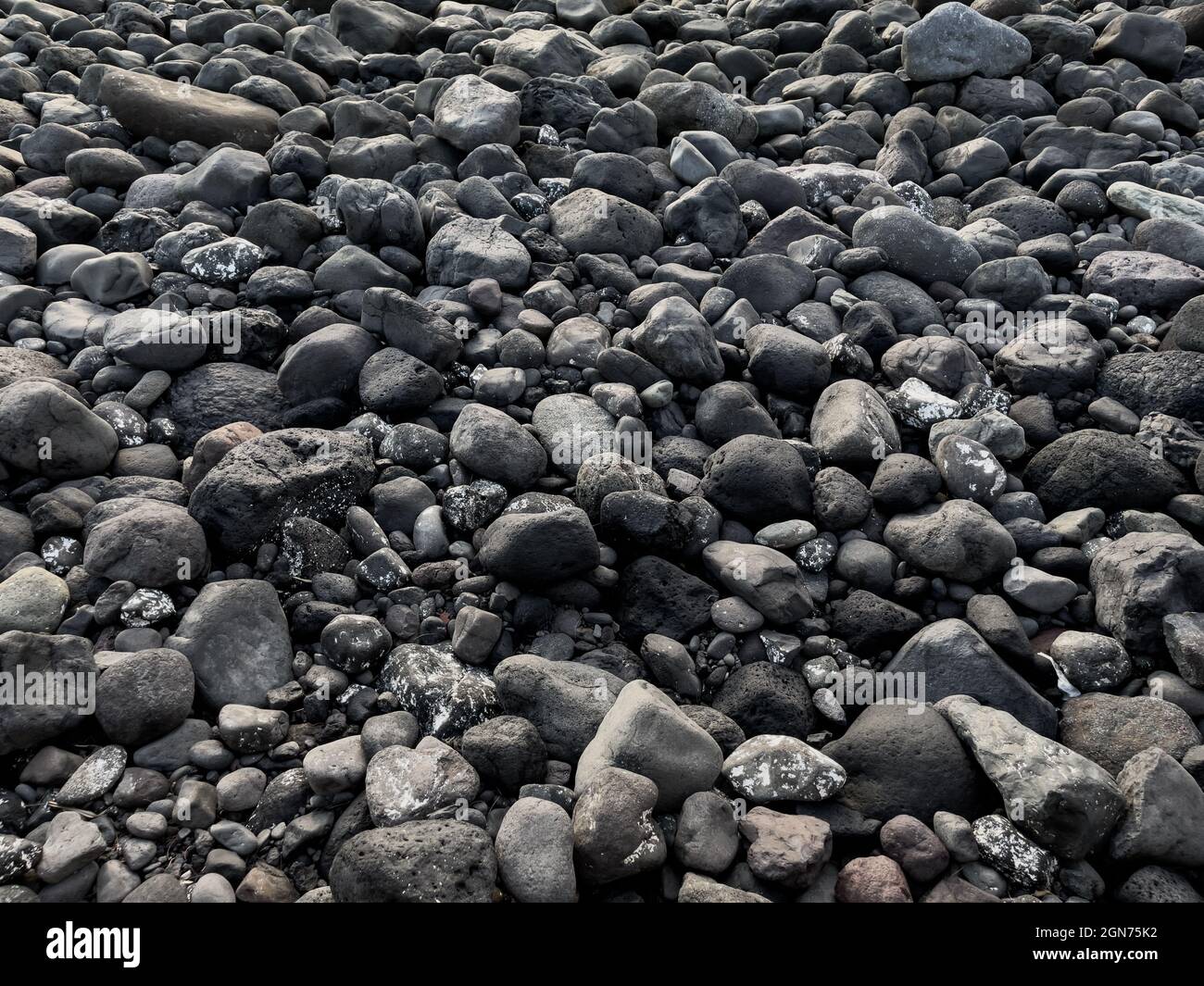 Black volcanic rock mixed with smooth stones Stock Photo - Alamy