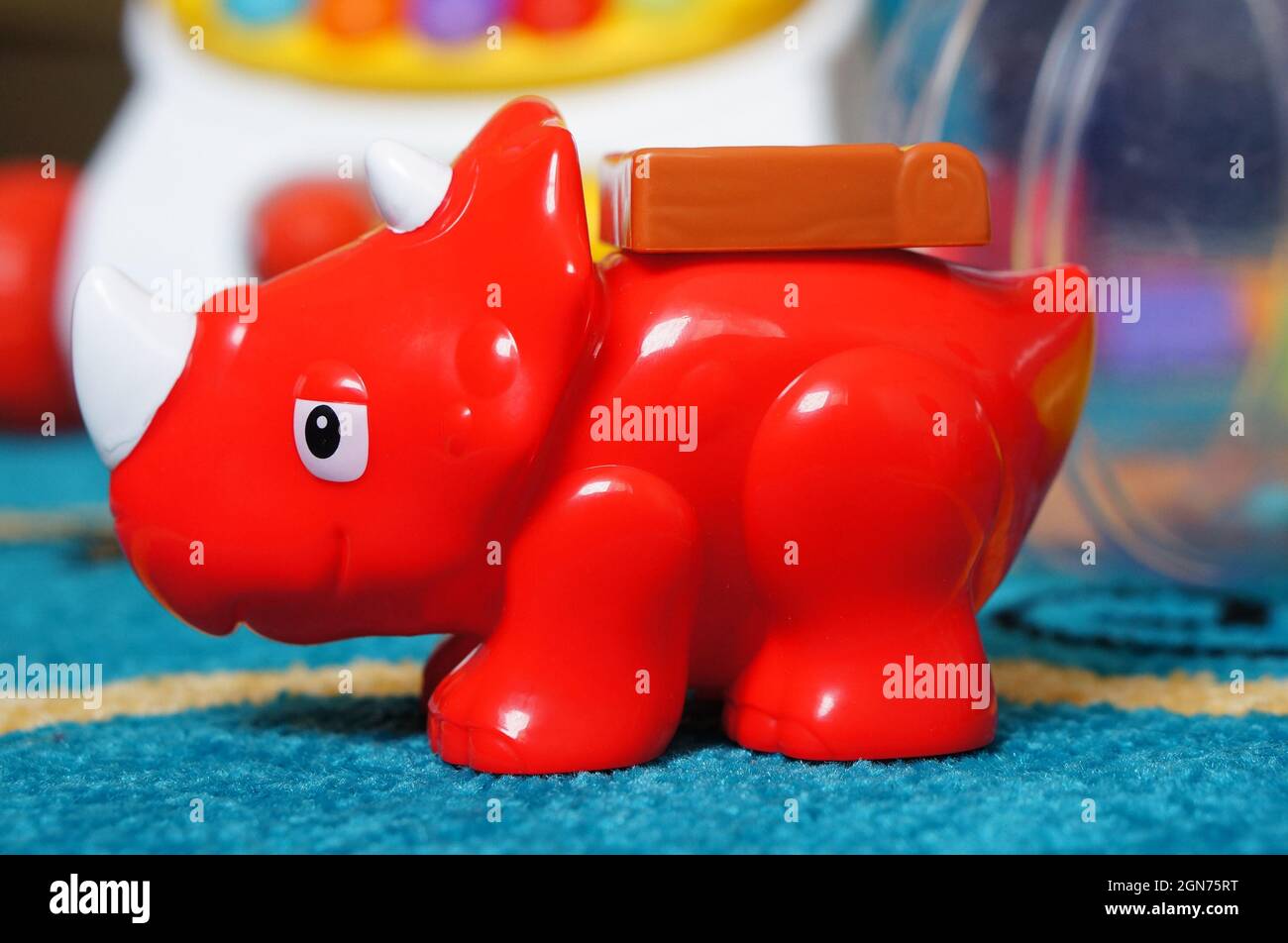 Red plastic toy of a triceratops dinosaur on the floor Stock Photo - Alamy