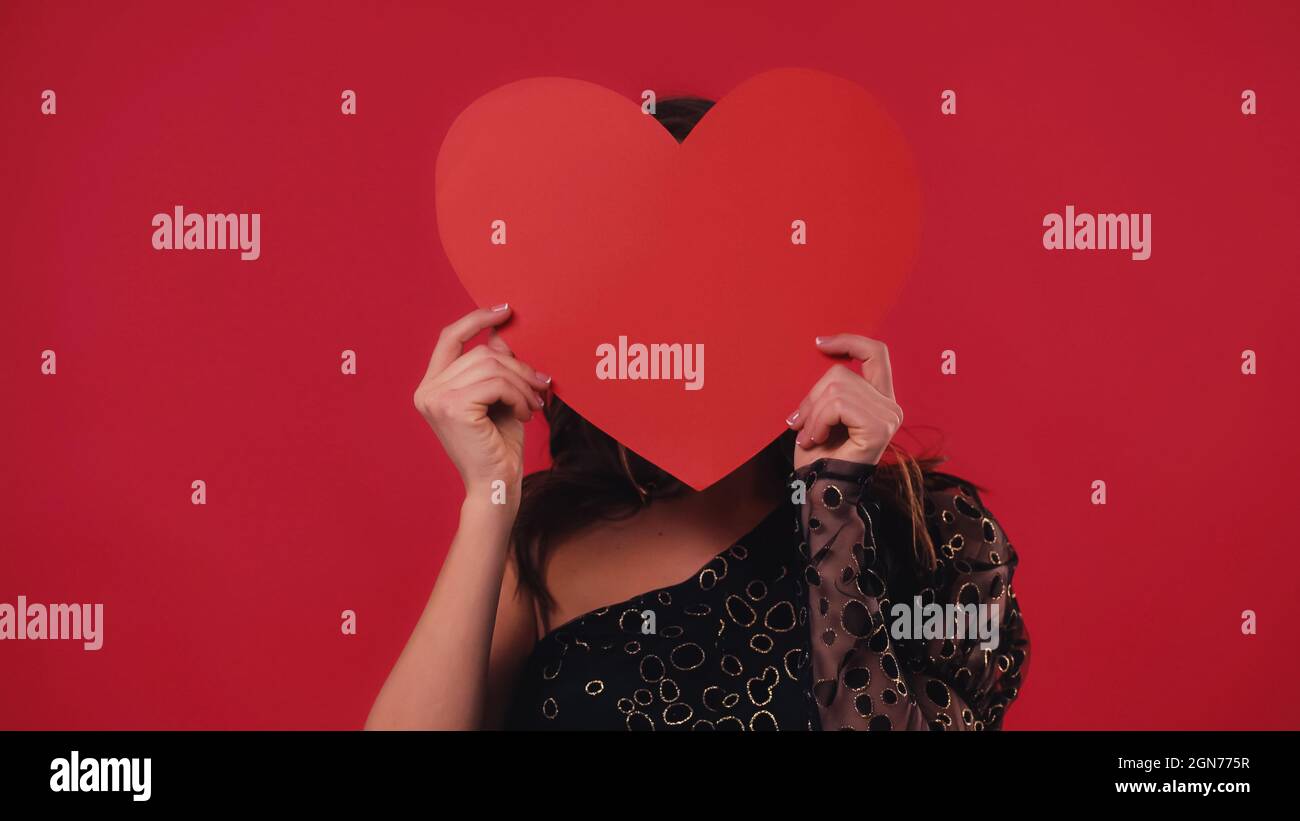 woman holding paper heart and covering face isolated on red Stock Photo ...