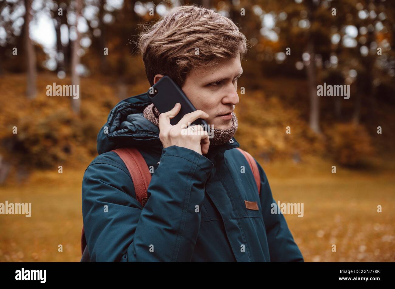 Portrait of a man in warm jacket talking on the phone in the park Stock ...