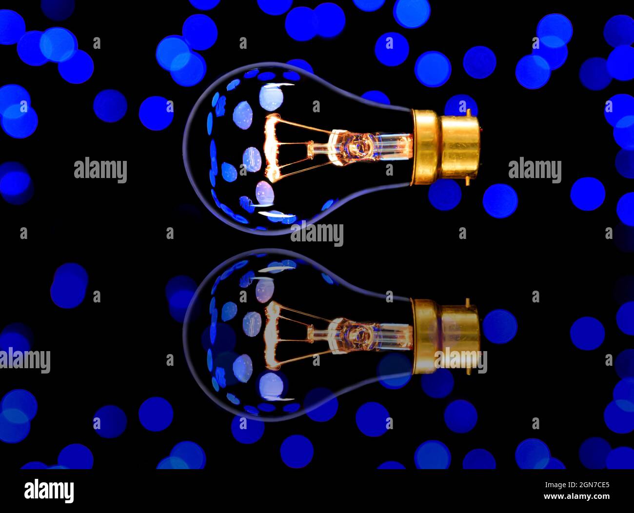Soft glowing light bulb with reflection and black background with blue ...