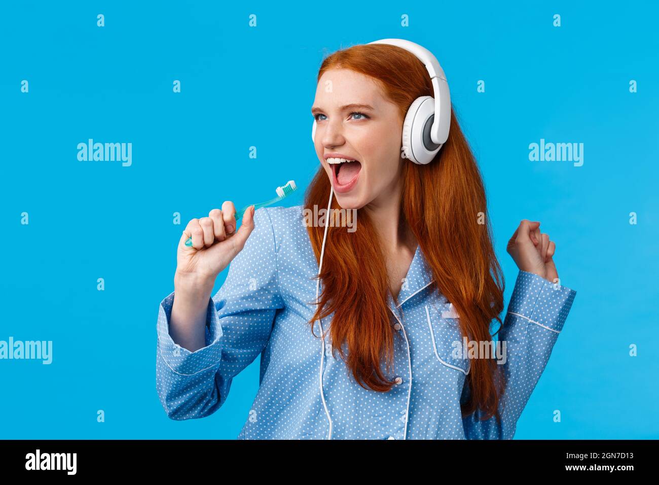 Sassy good-looking redhead female in pyjama having fun, listening music ...