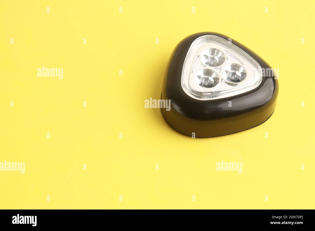 Triangular black flashlight on a yellow surface Stock Photo - Alamy