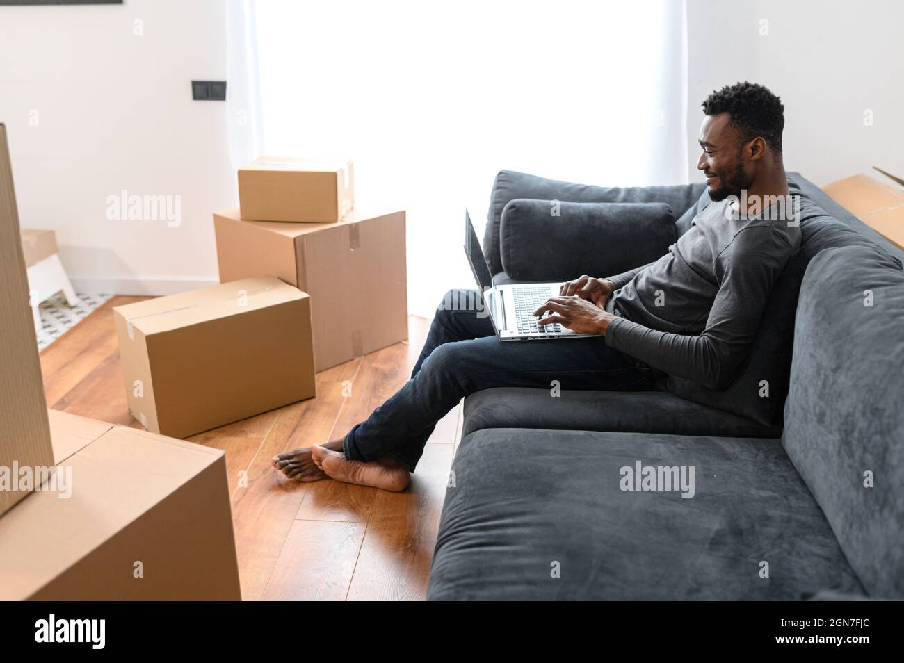 Side view at satisfied African-American guy sitting on the comfortable ...