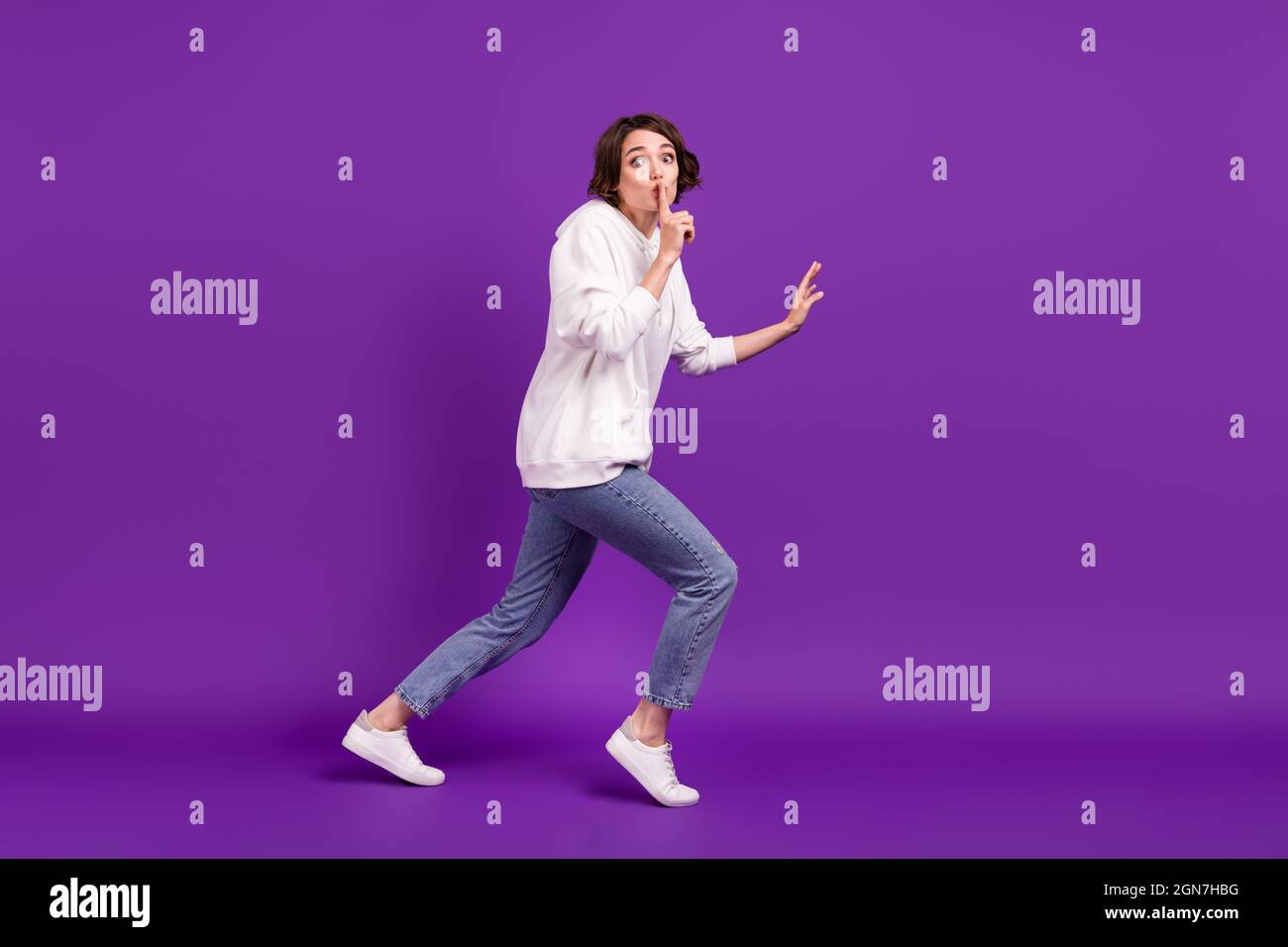 Full size photo of young serious girl show shut-up gesture running away ...