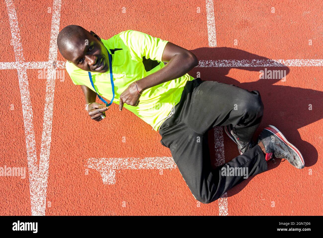 african american runner showing his gold medal on the running track ...