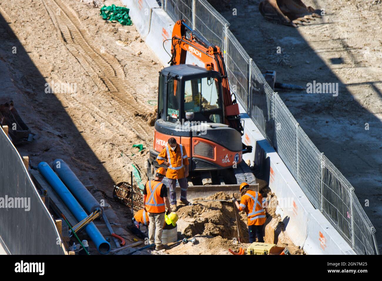 SYDNEY, AUSTRALIA - Sep 03, 2021: A small excavator and three workers ...