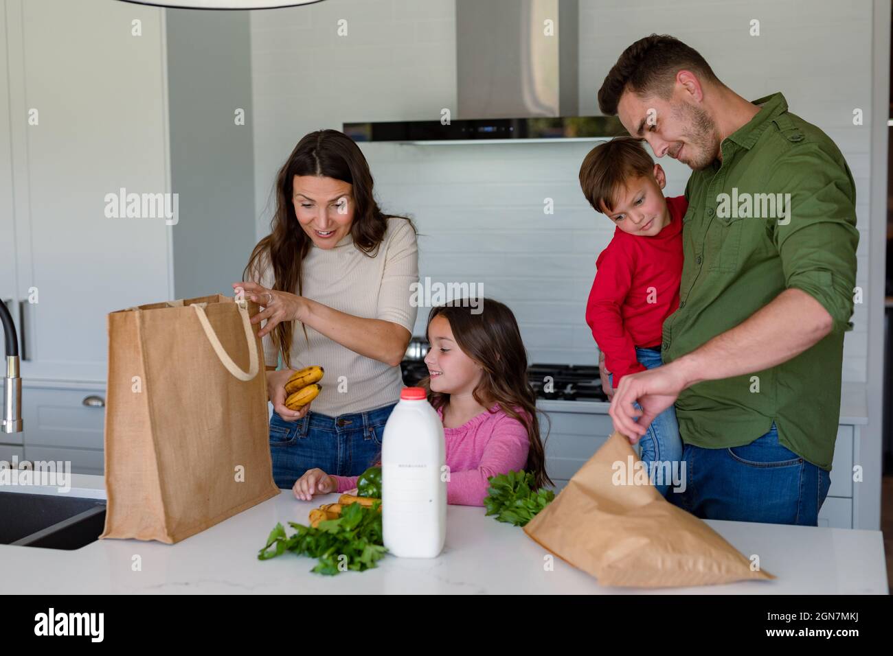 Happy caucasian family unpacking groceries together in kitchen Stock ...