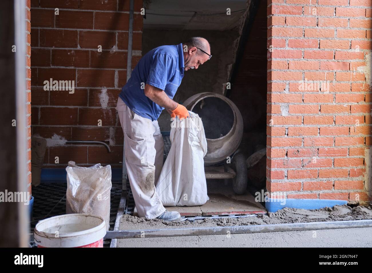 Construction worker loading a sandbag into the concrete mixer Stock ...
