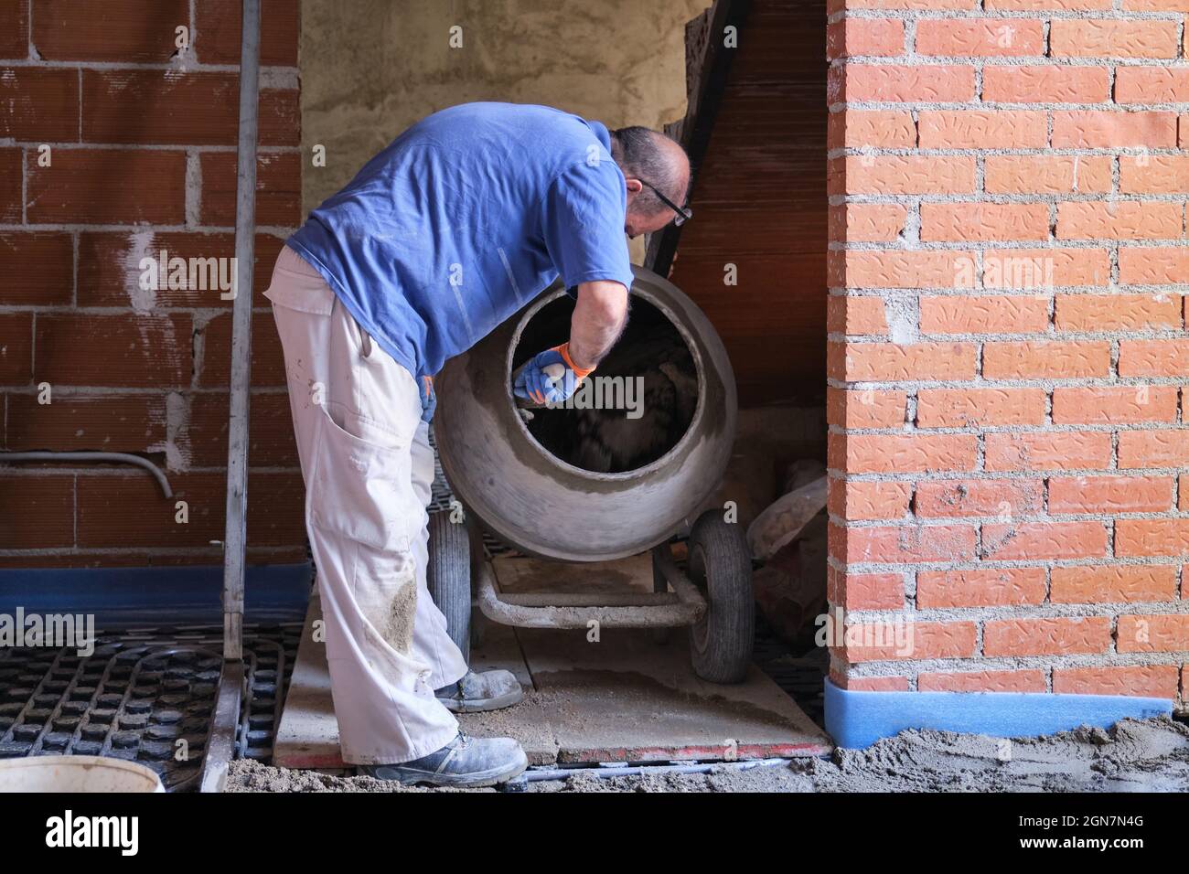 Construction worker checking the quality of the concrete into the mixer ...