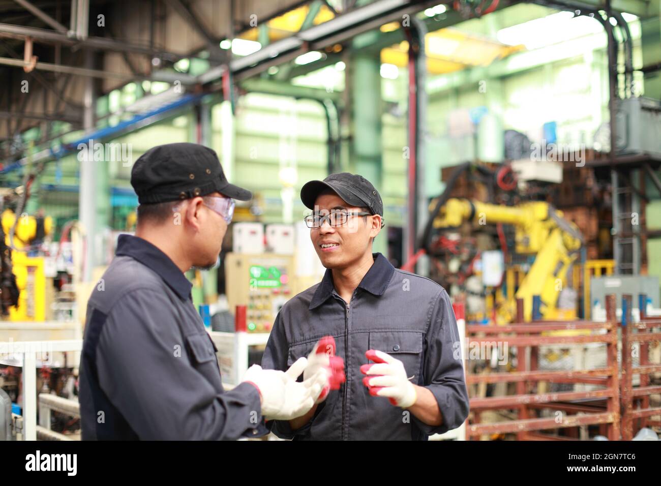 two factory workers discussing with machine industry in the background ...