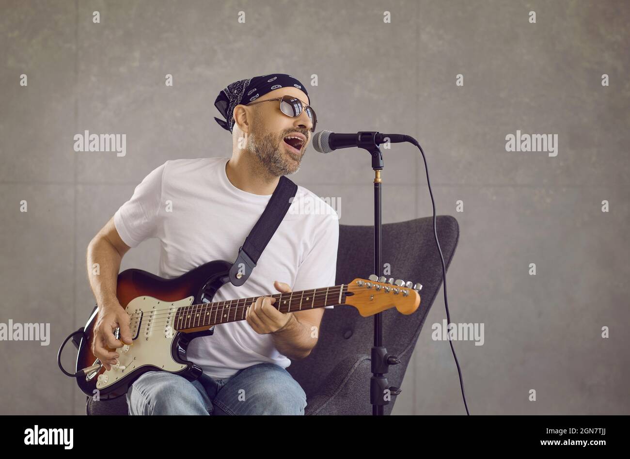 Portrait of male musician who sings song into microphone and plays ...