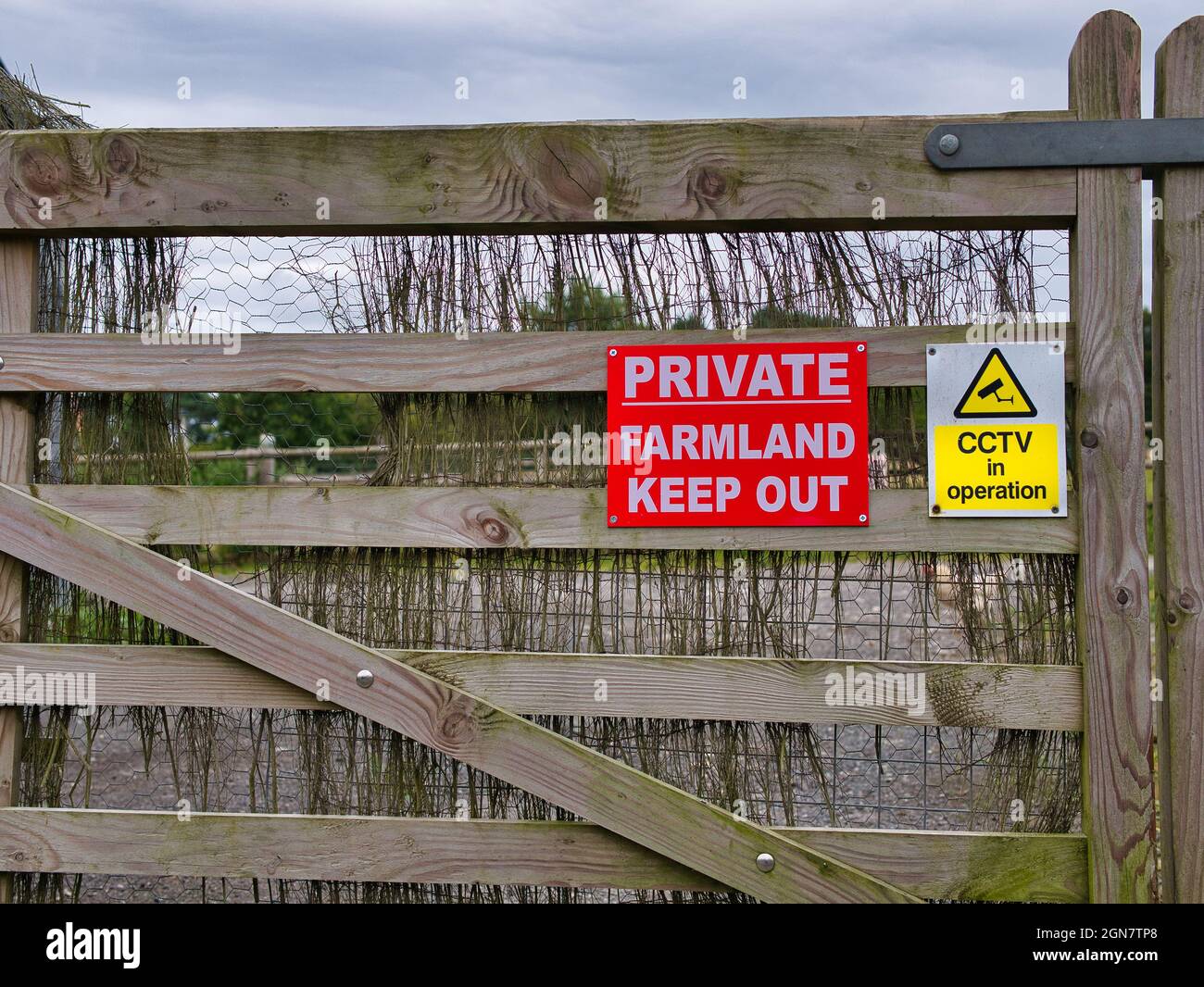Signs on a wooden farmyard gate warning that the area is private ...