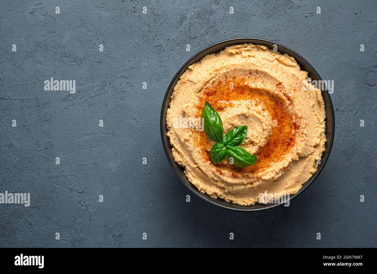 Traditional hummus with paprika and olive oil on a dark background. Top ...