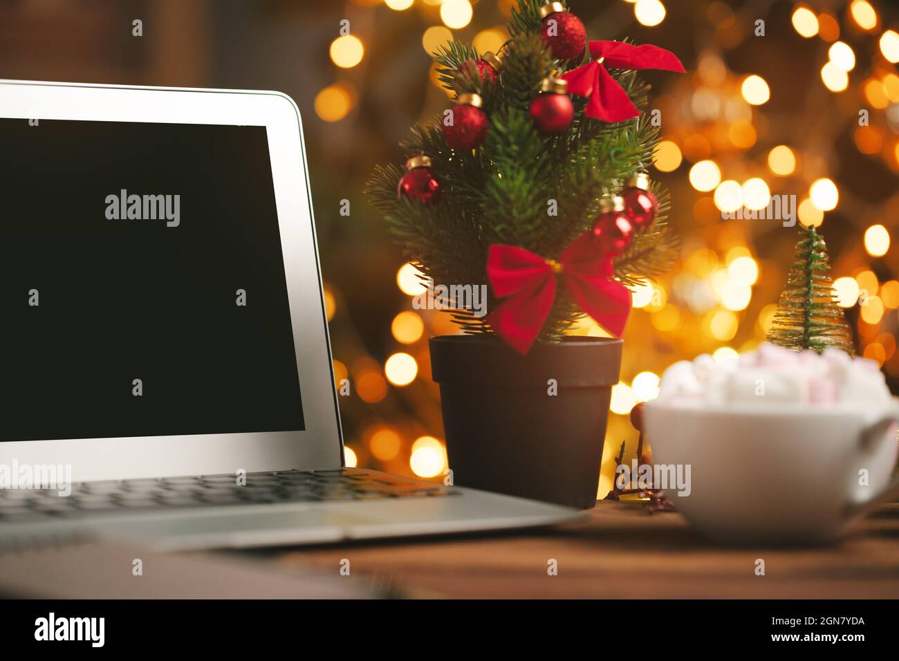Wooden desk with computer with blank screen against blurred christmas ...