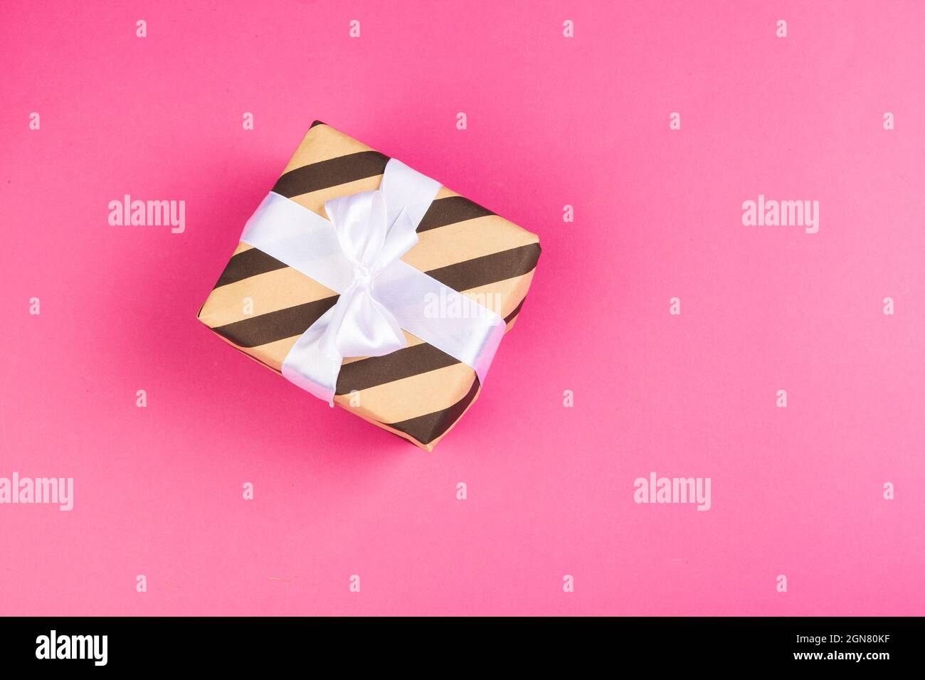 Top view of a decorated present with a bow on pink background Stock ...